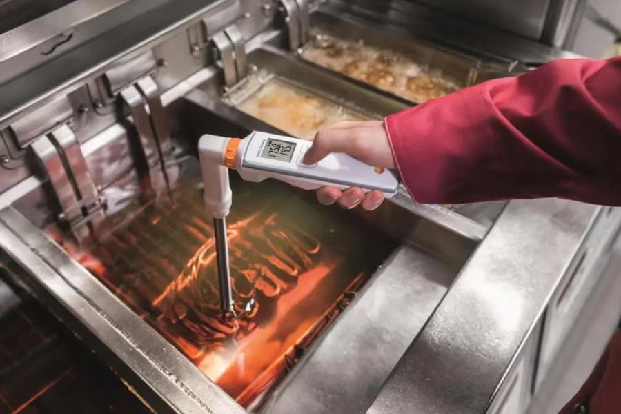 Employees at the deep fryer with measuring instruments